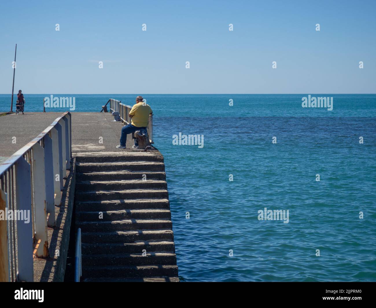 Lonely man on the pier. Rest on the seashore. Escape from everyday life ...