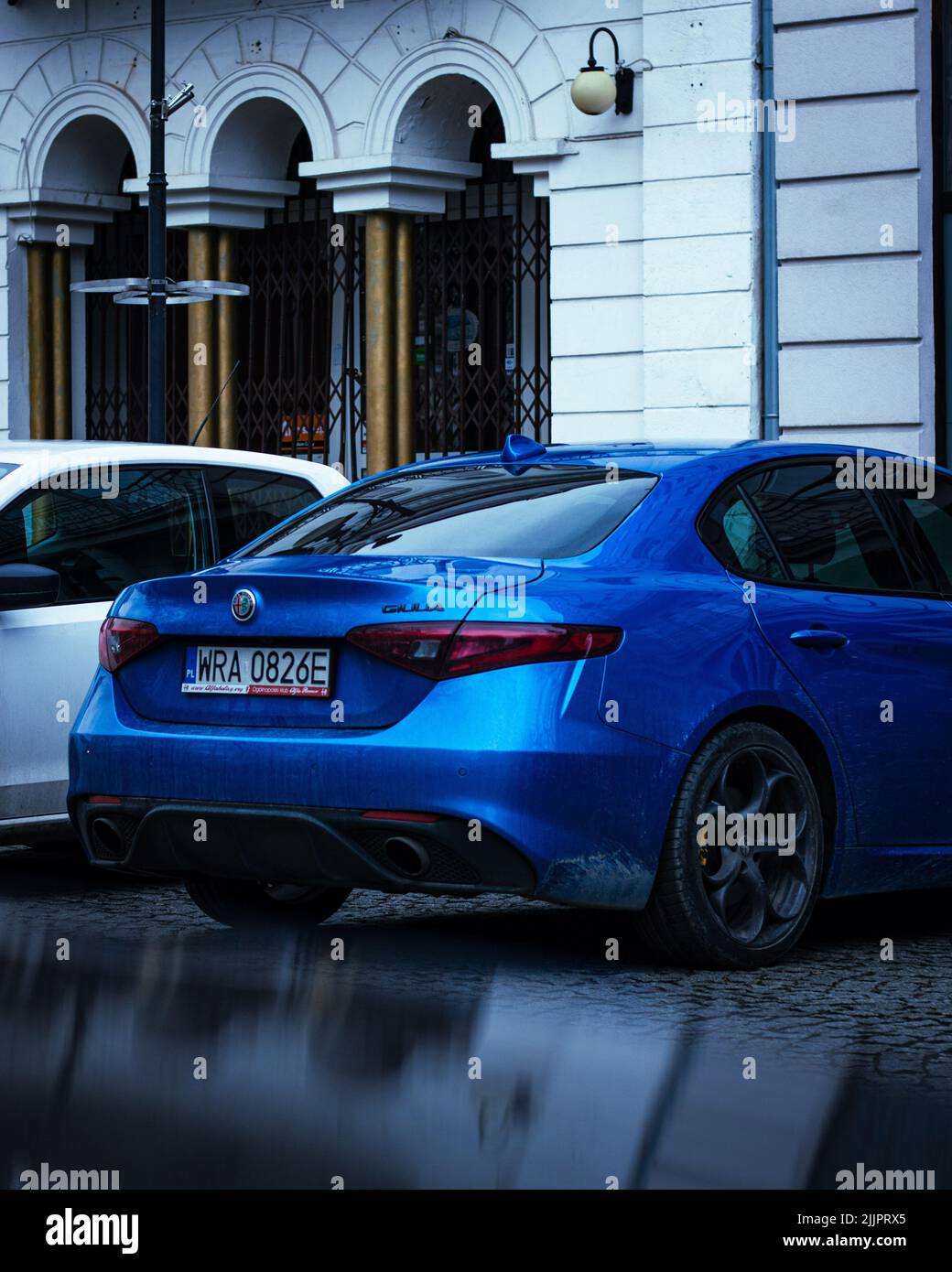 A blue Alfa Romeo Gulia Quadrifolgio parked near an antique building ...