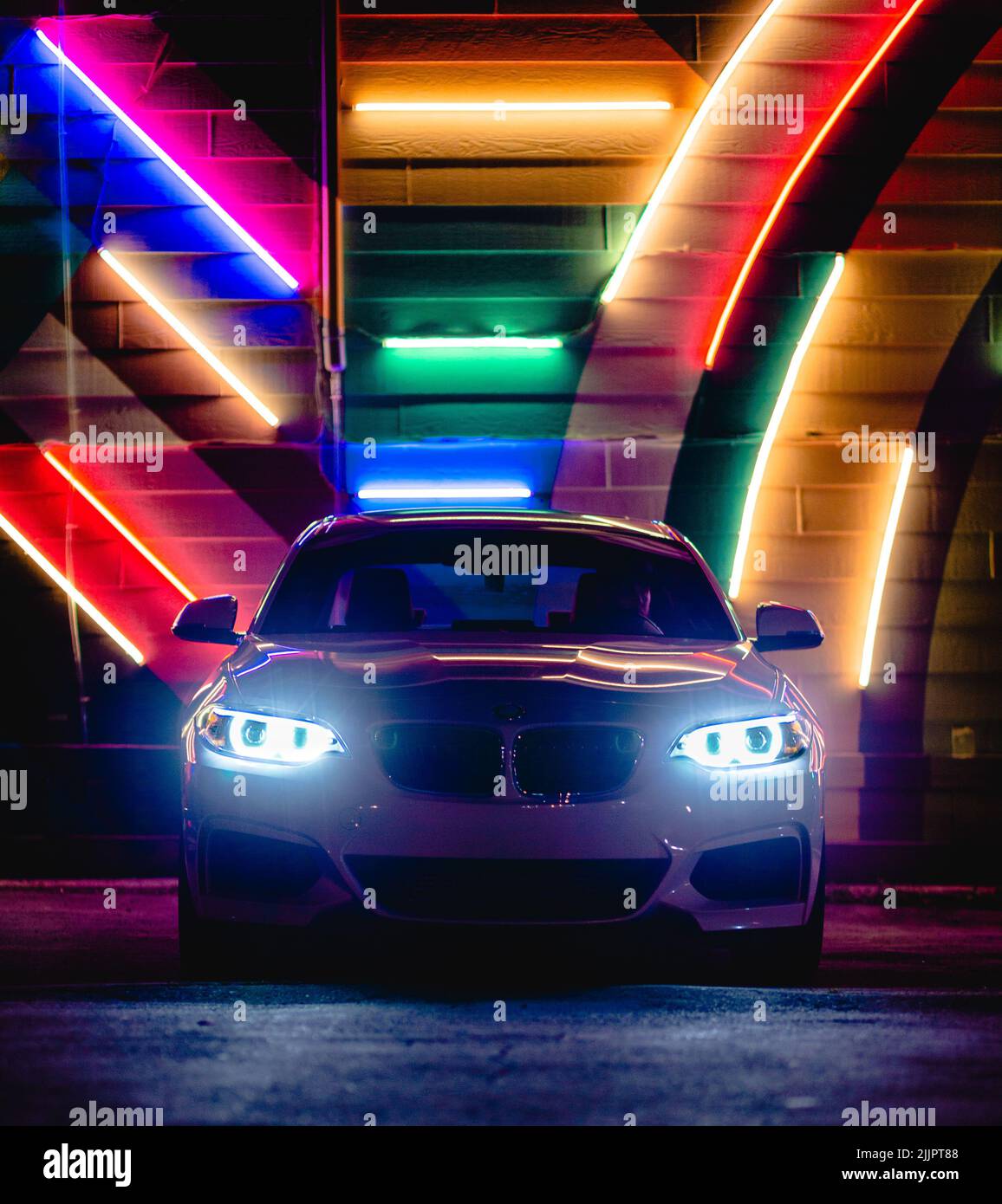 A White BMW sports car parked at night by the neon wall in Dartmouth ...