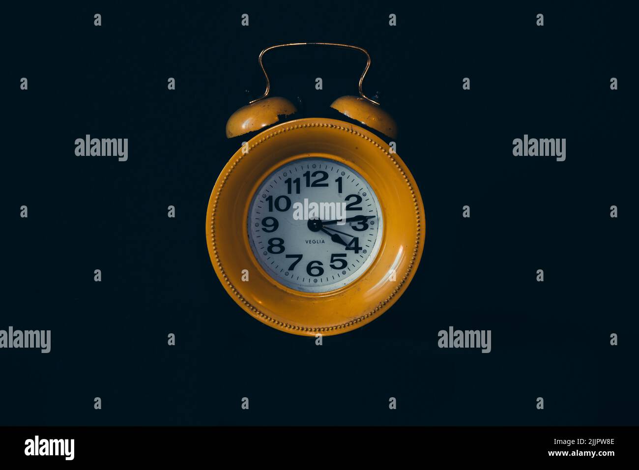 A classic yellow alarm clock isolated on a dark background Stock Photo ...