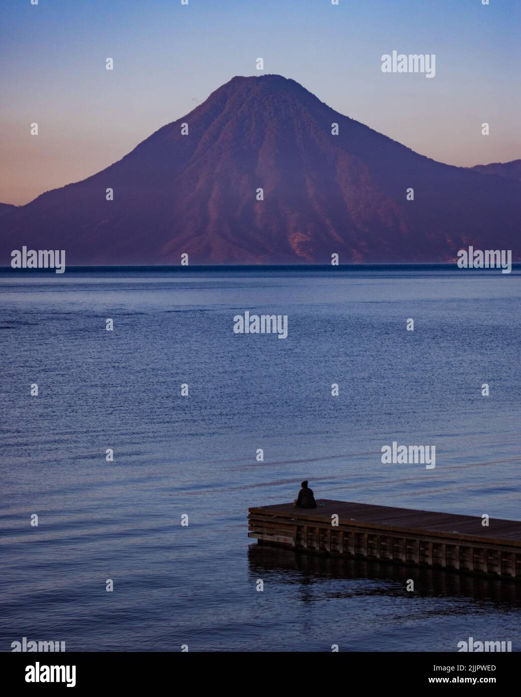 An aerial view of wooden bridge near sea in background of volcano in ...