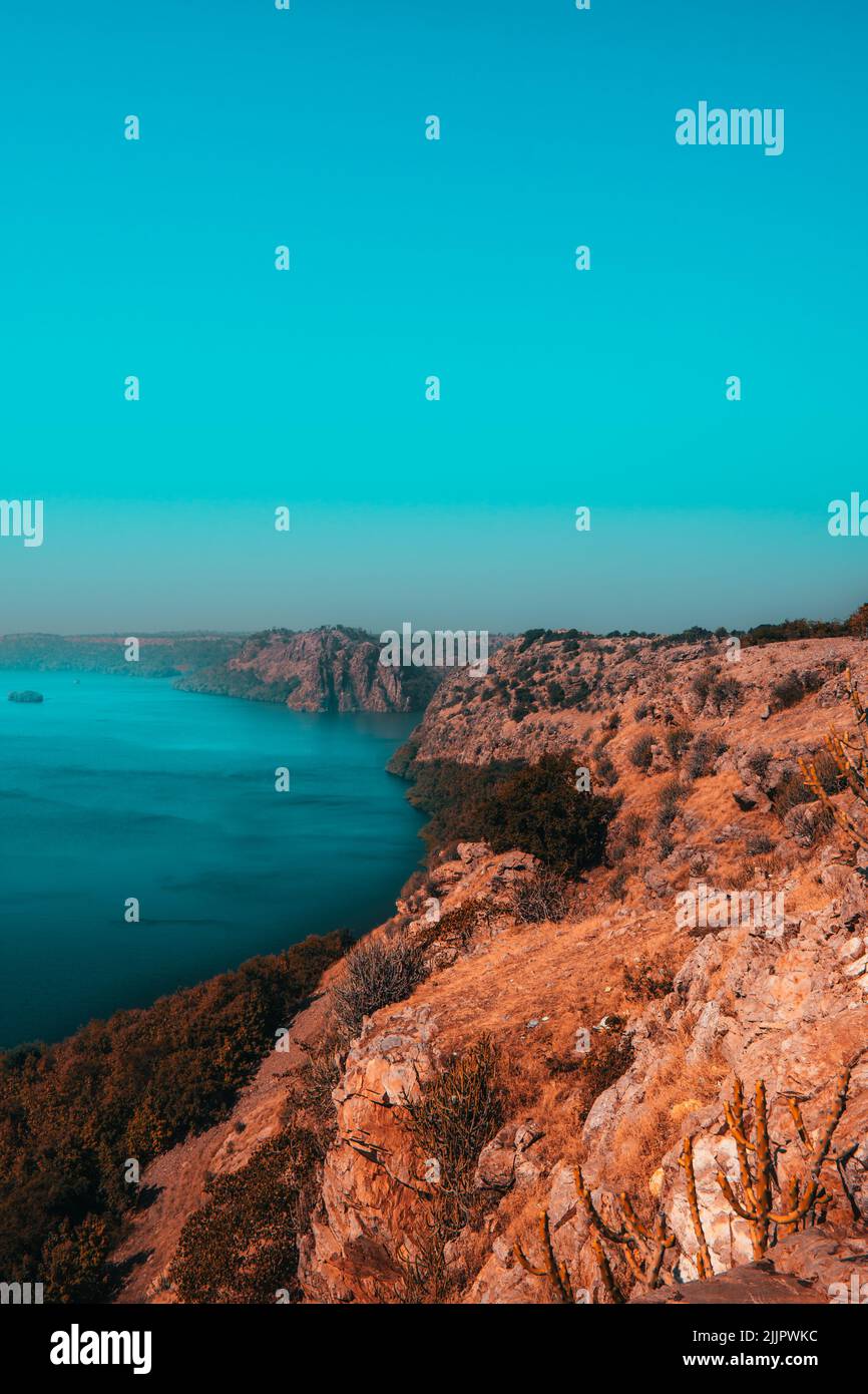 A vertical shot of a bright blue lake with brown cliffs Stock Photo - Alamy