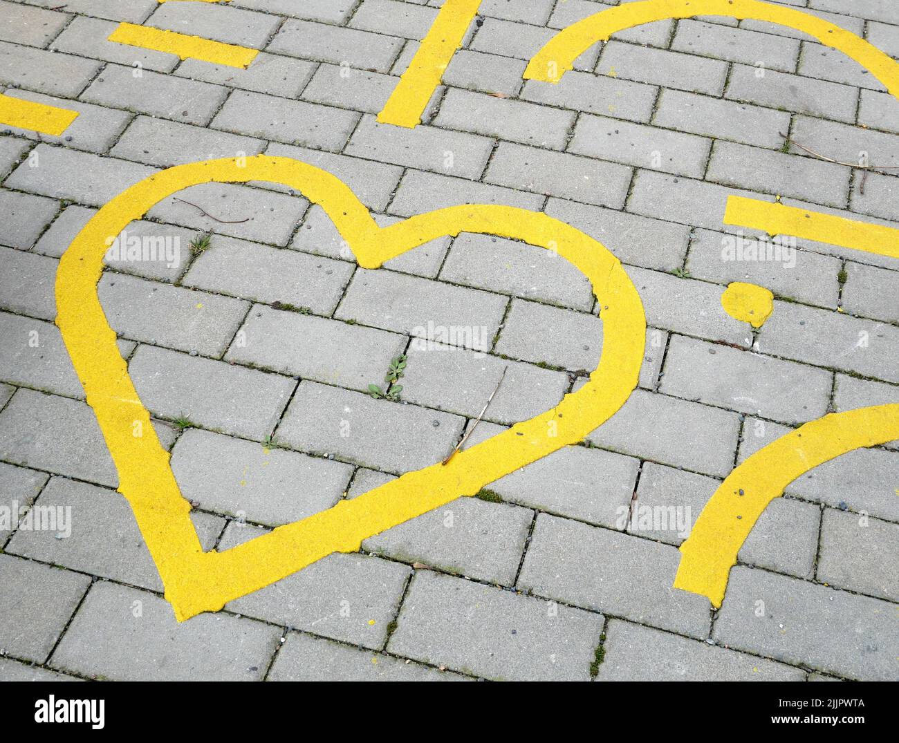 Yellow heart symbol on a parking lot and pavement Stock Photo - Alamy