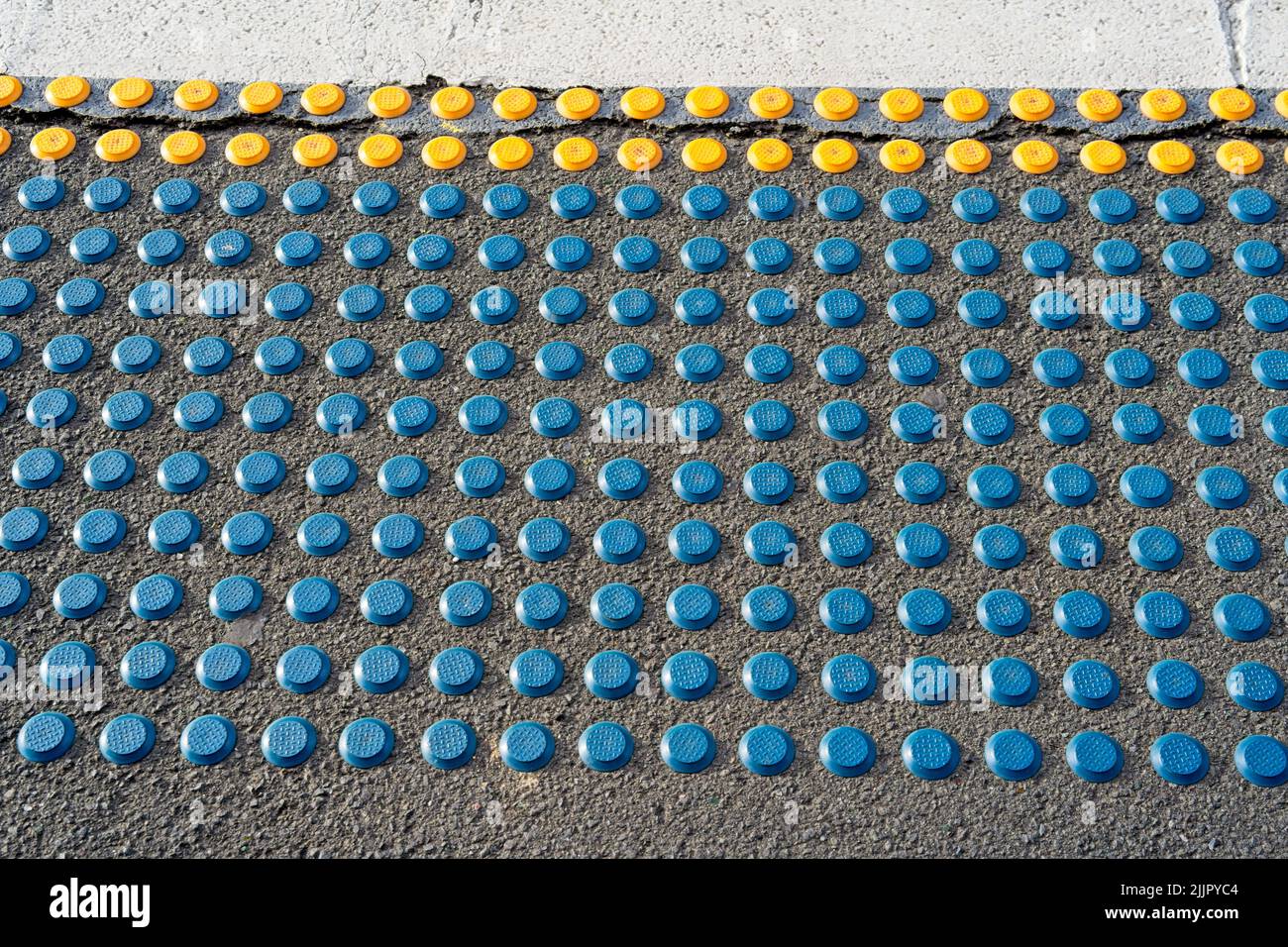The tactile dots on the edge of a train station platform Stock Photo ...