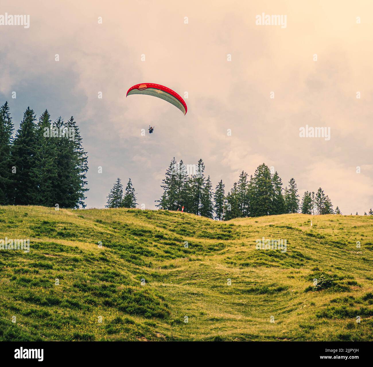 A paraglider flying from mountain under the cloudy skies Stock Photo ...