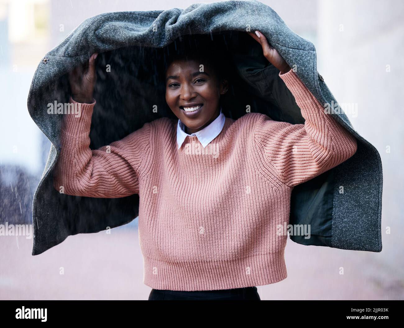 No umbrella, no problem. a young businesswoman using a jacket to cover ...