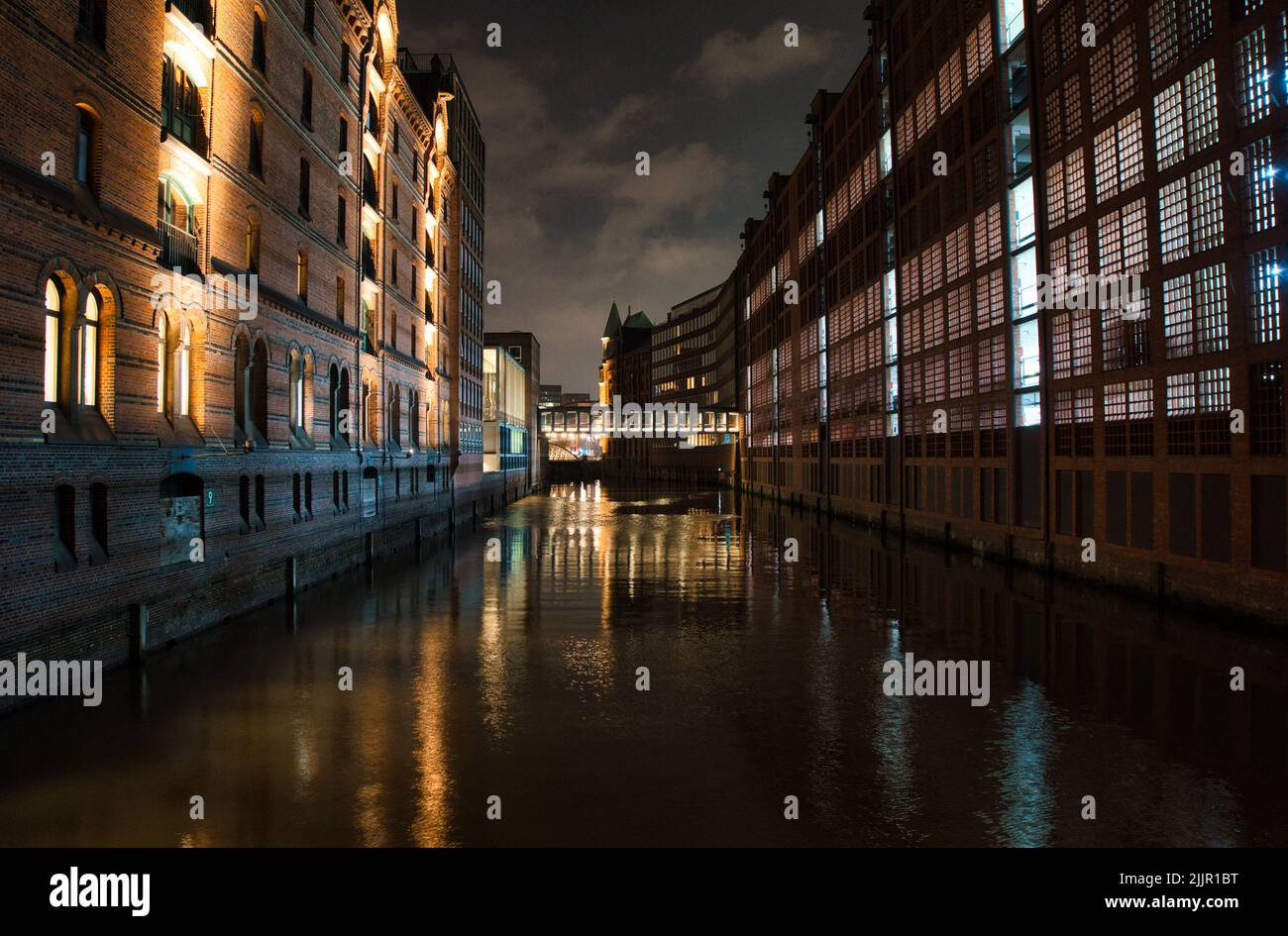 A reflection of illuminated buildings in canal at night in Hamburg ...