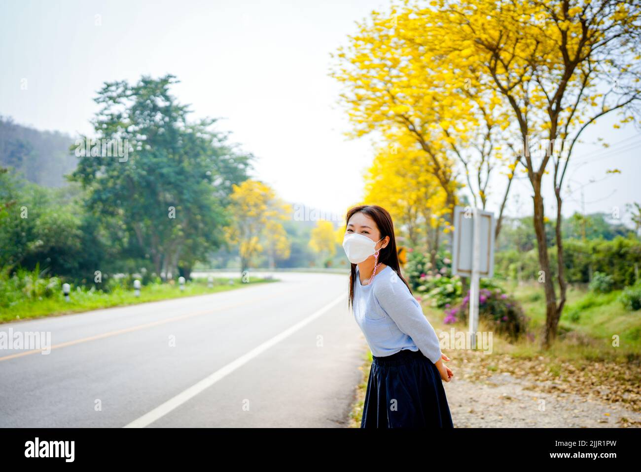 A beautiful woman with a face mask on the side of the road surrounded ...