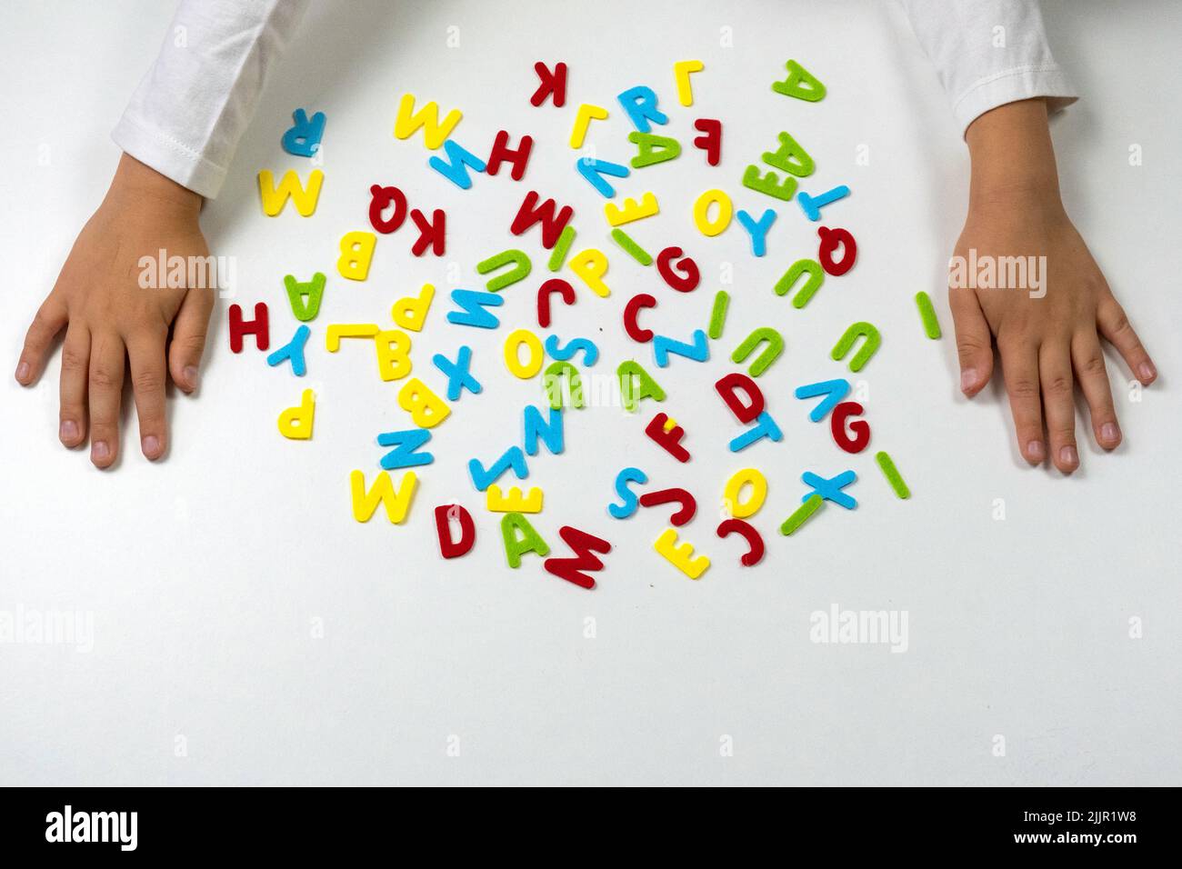 Colorful letters. The child's hands lay out colored letters on the ...