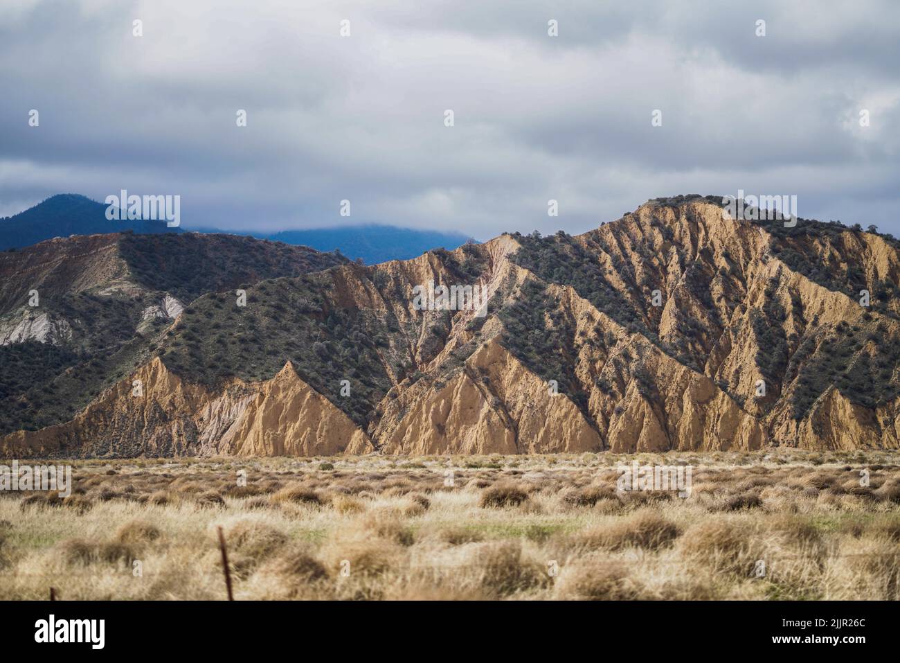 A landscape with ridge arid mountains against the cloudy sky background ...
