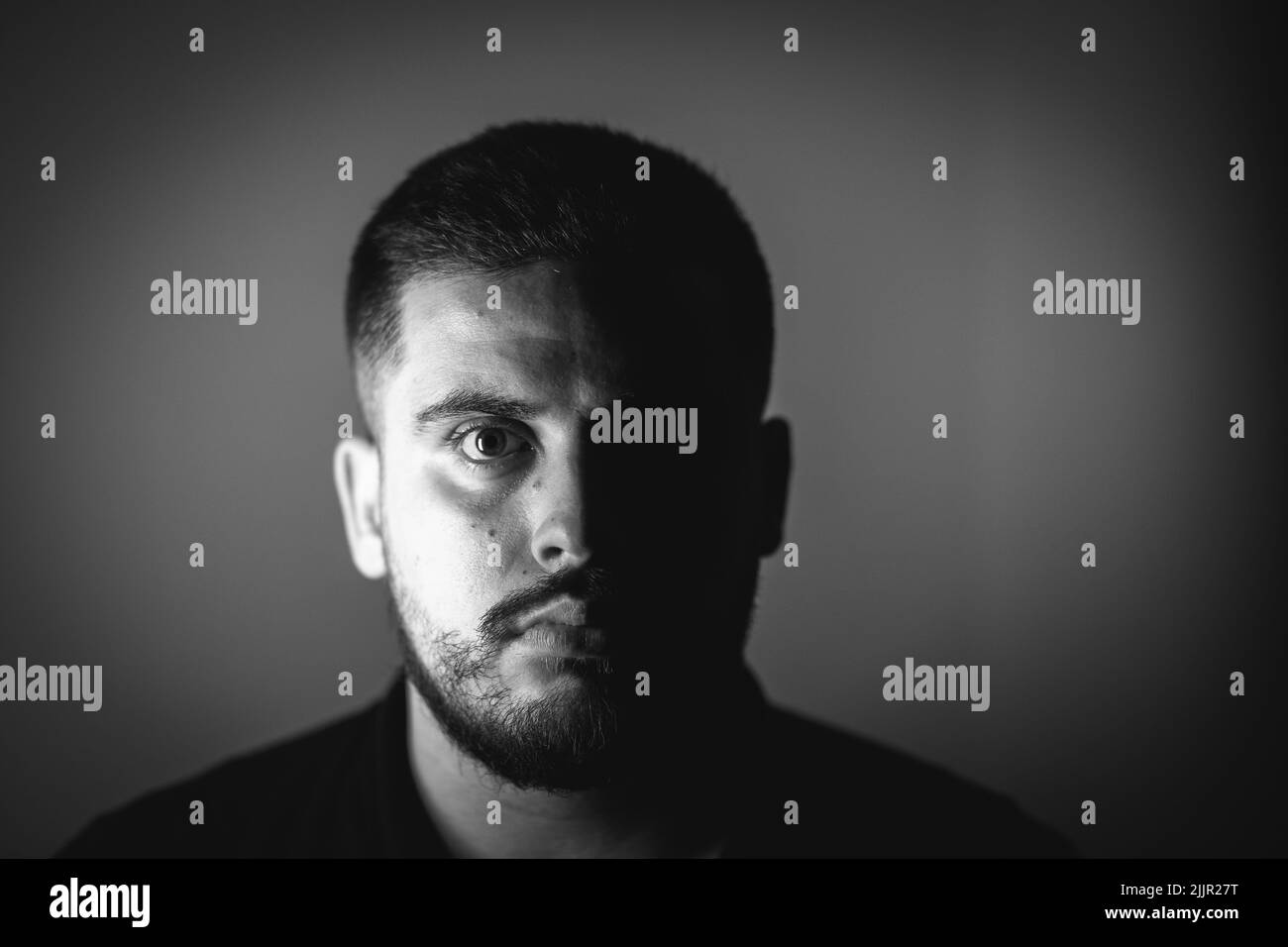 A grayscale portrait of a young Caucasian male with a serious face ...