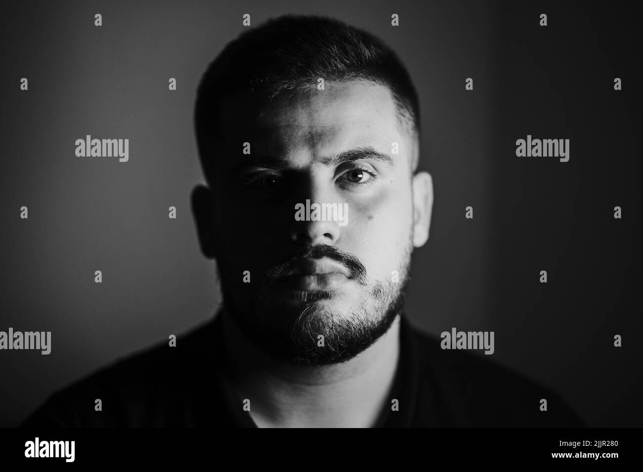 A grayscale portrait of a serious young Caucasian male with a shadow ...