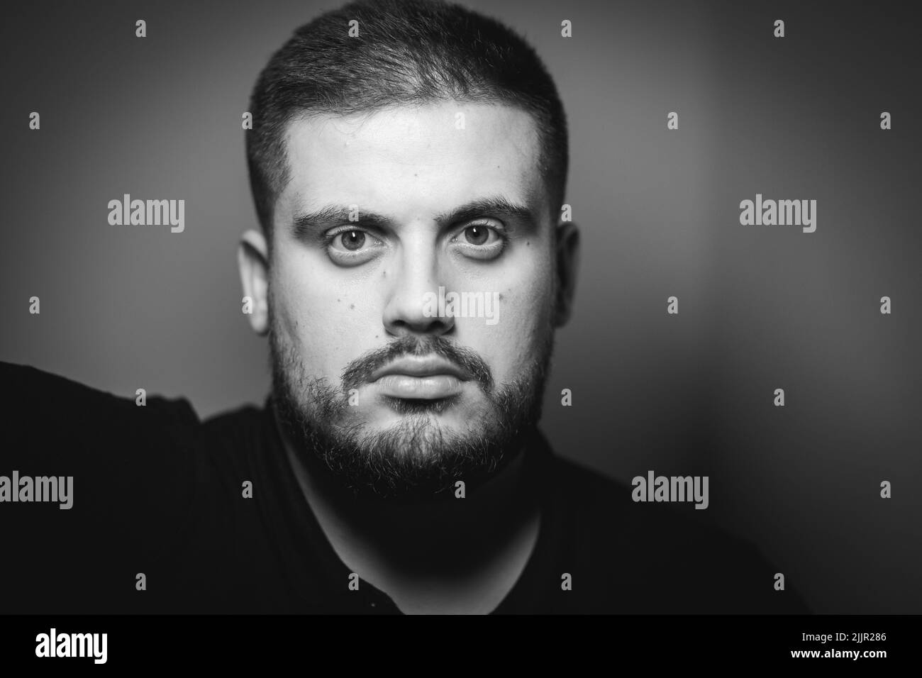 A grayscale portrait of a young Caucasian male with a serious face ...