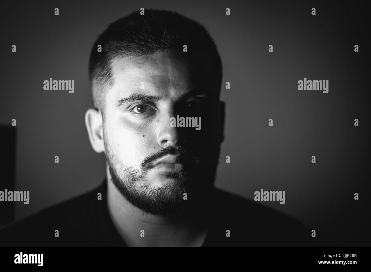 A grayscale portrait of a young Caucasian male with a serious face ...