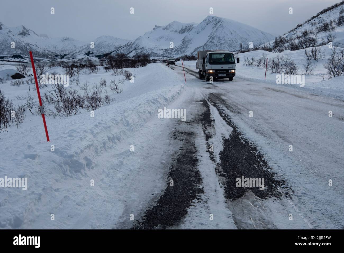 A white truck on an icy trail through snowy mountains in the Lofoten ...