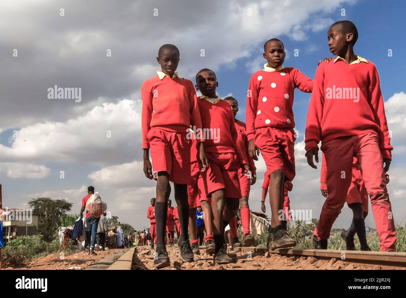 Pupils walking home from school through a train line running through ...