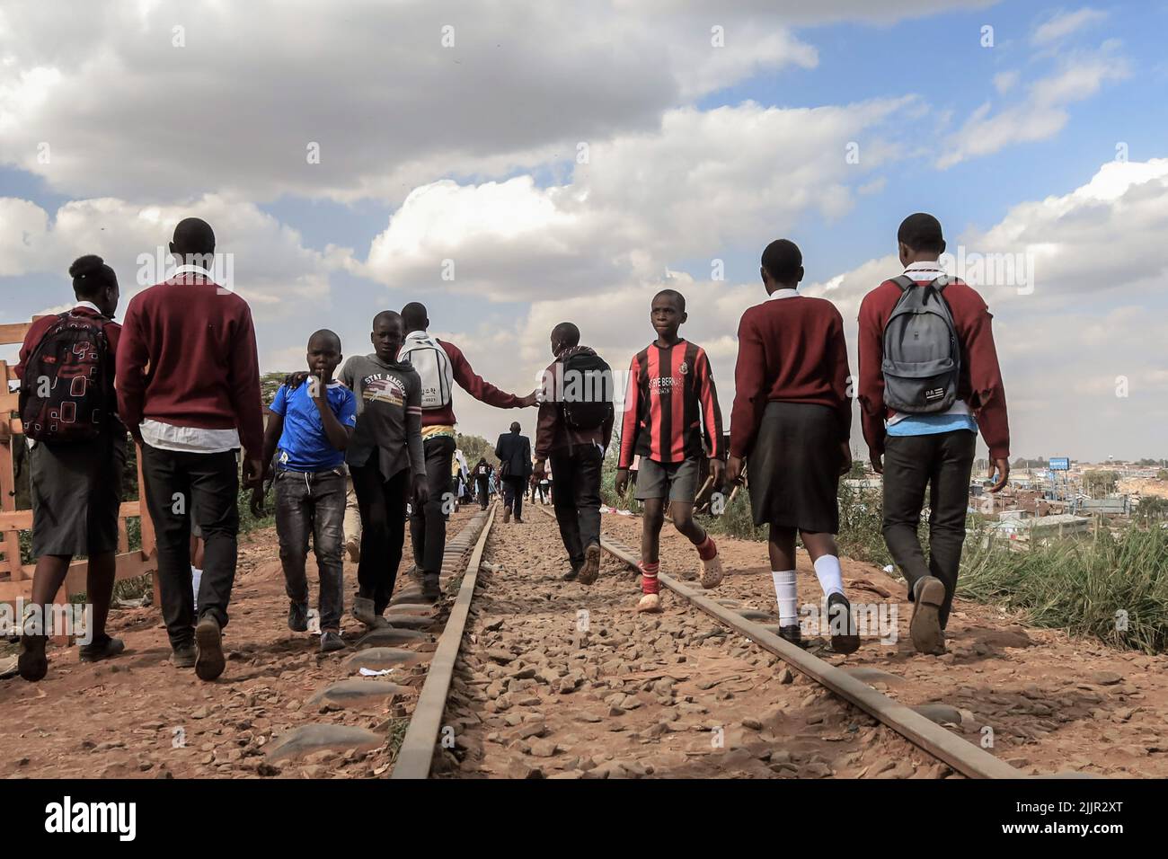 Students walking home from school through a train line running through ...