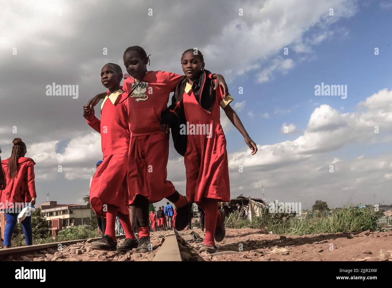 Pupils walking home from school through a train line running through ...