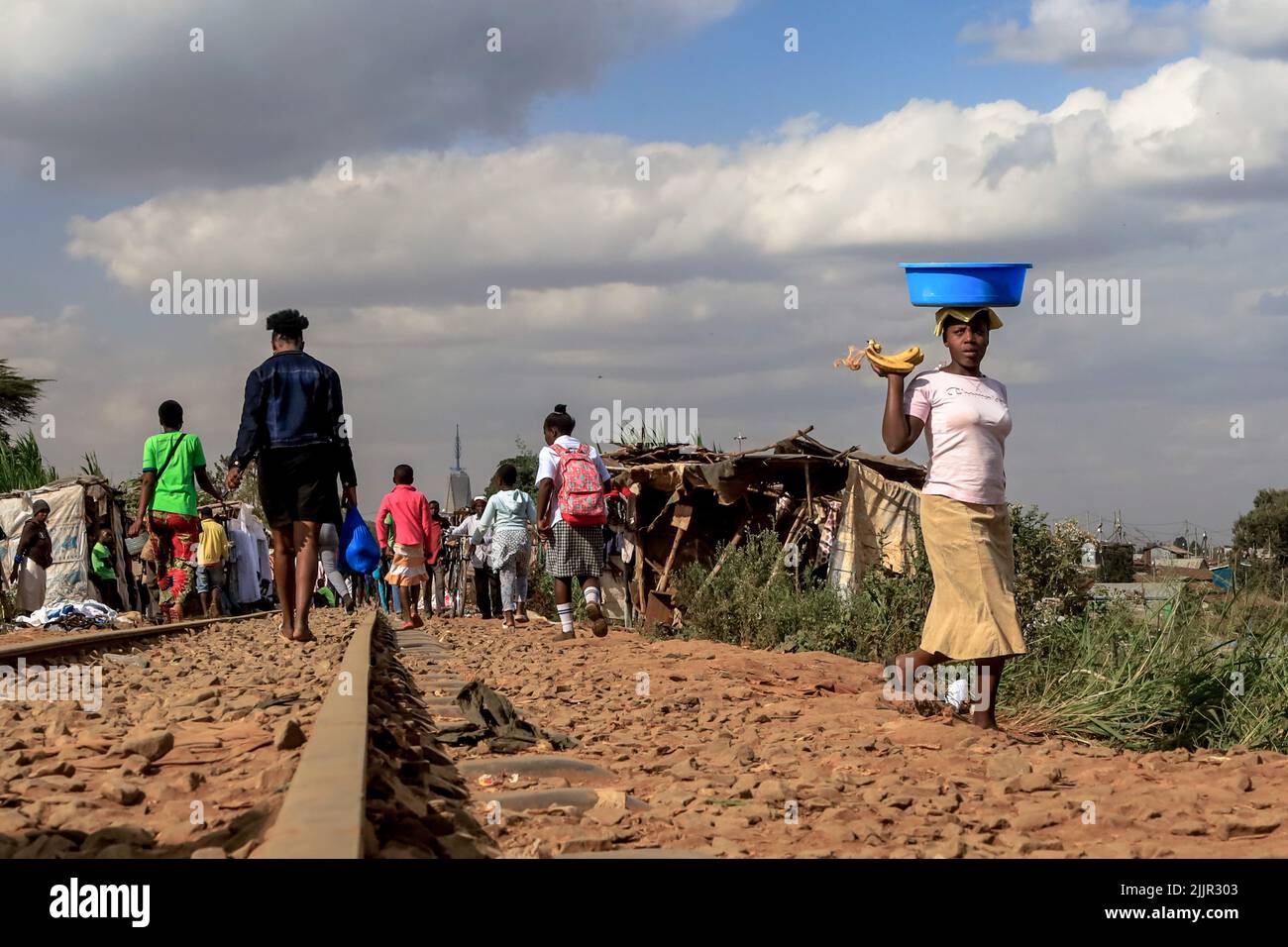Residents walking by a train line running through Kibera Slum of ...