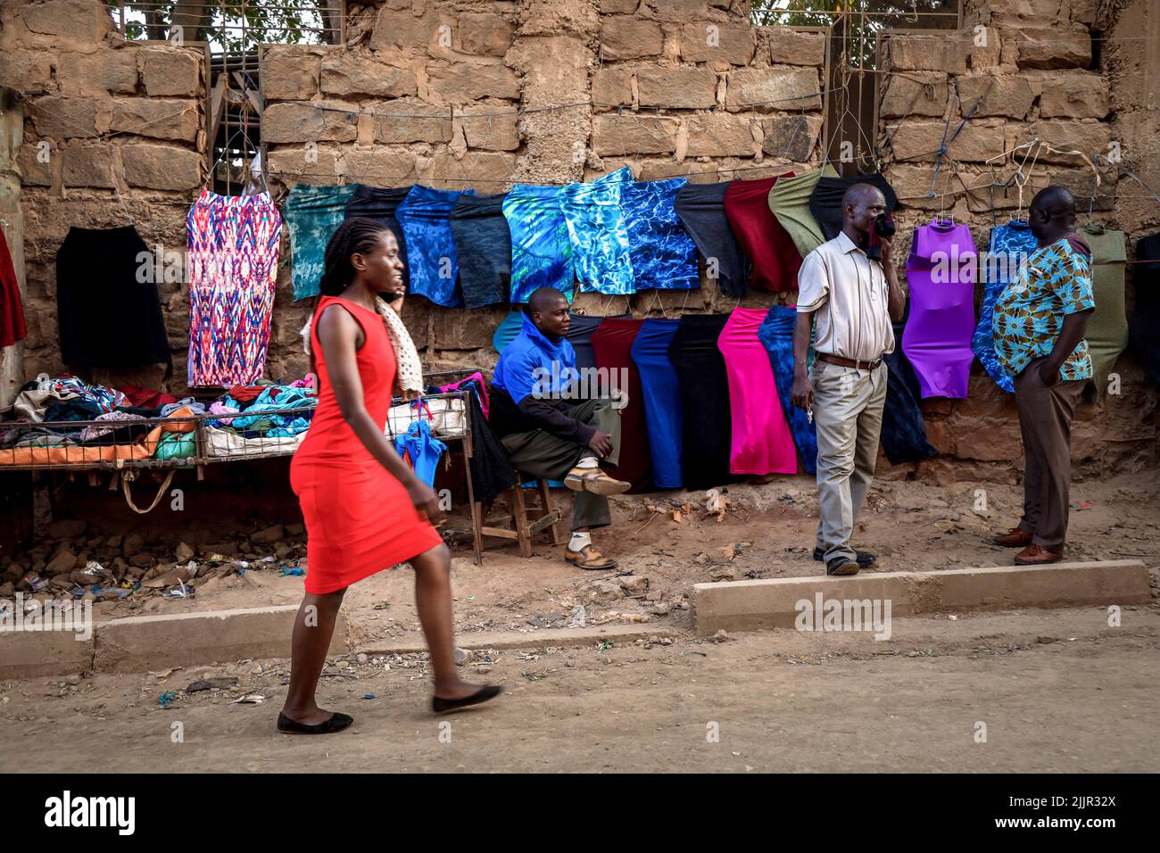 A woman walks past a group of men selling clothes by the streets in ...