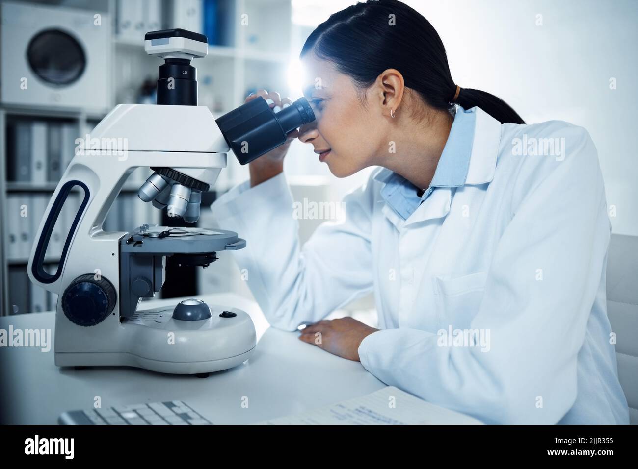 Its all molecules over matter. a young scientist using a microscope in ...