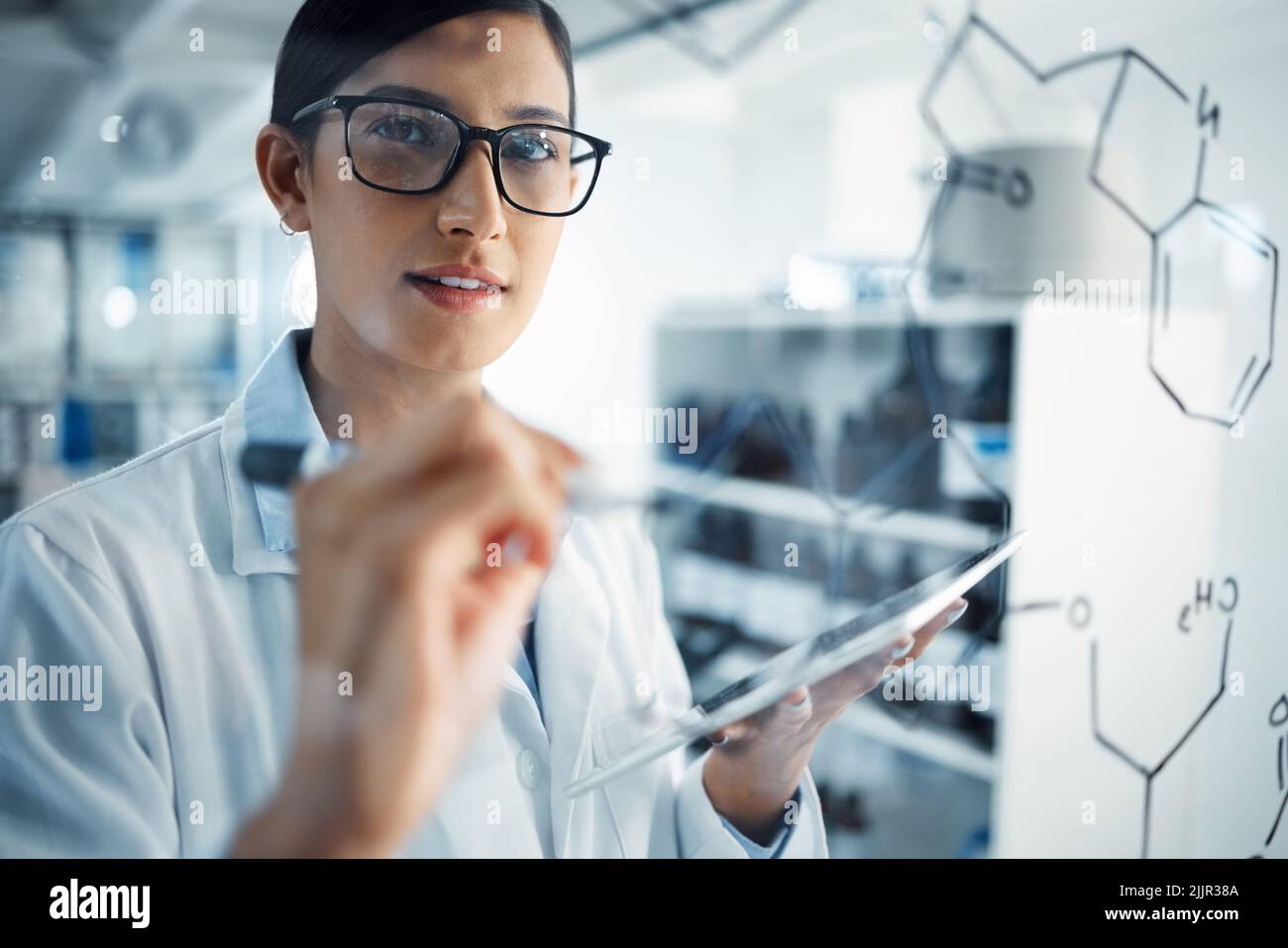 The brains behind the big change. a young scientist solving equations on a glass screen in a ...
