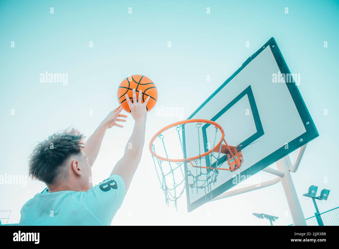 A vertical of a young male jumping and dunking a basketball into the ...