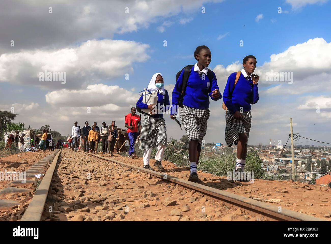 Students walking home from school through a train line running through ...