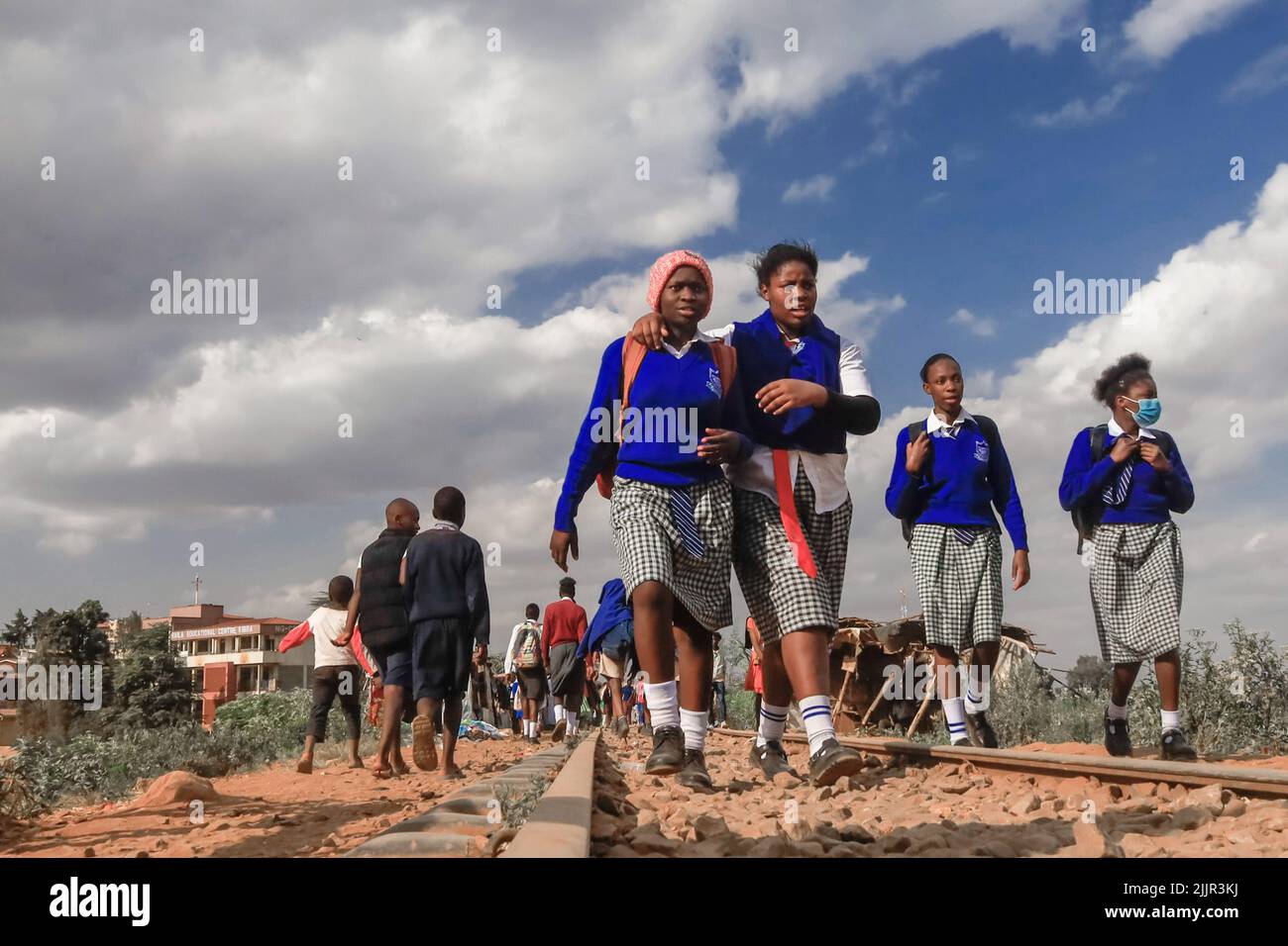 Students walking home from school through a train line running through ...