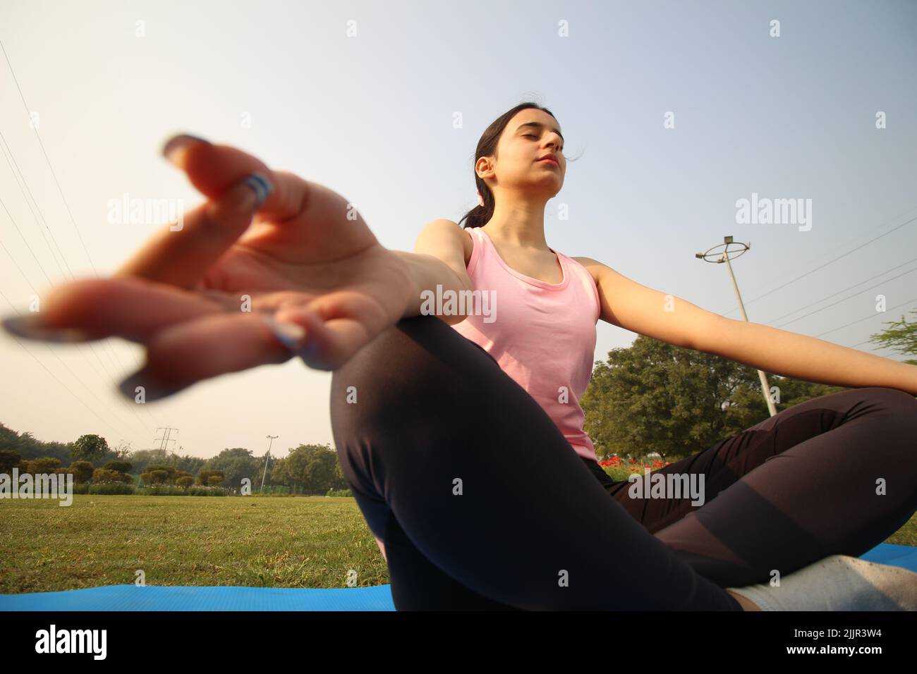 A low angle of a South Asian female doing yoga in the park - a healthy ...