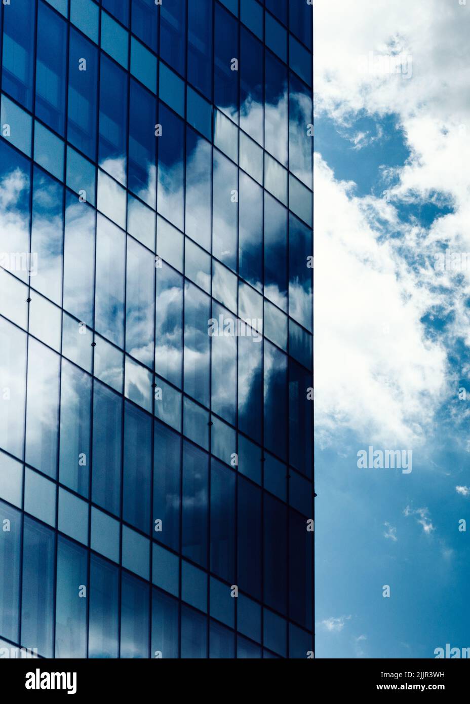 A vertical shot of the reflections of clouds on the facade of a modern ...