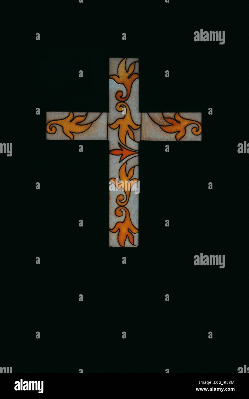 A vertical closeup shot of the cross with patterns on the black ...
