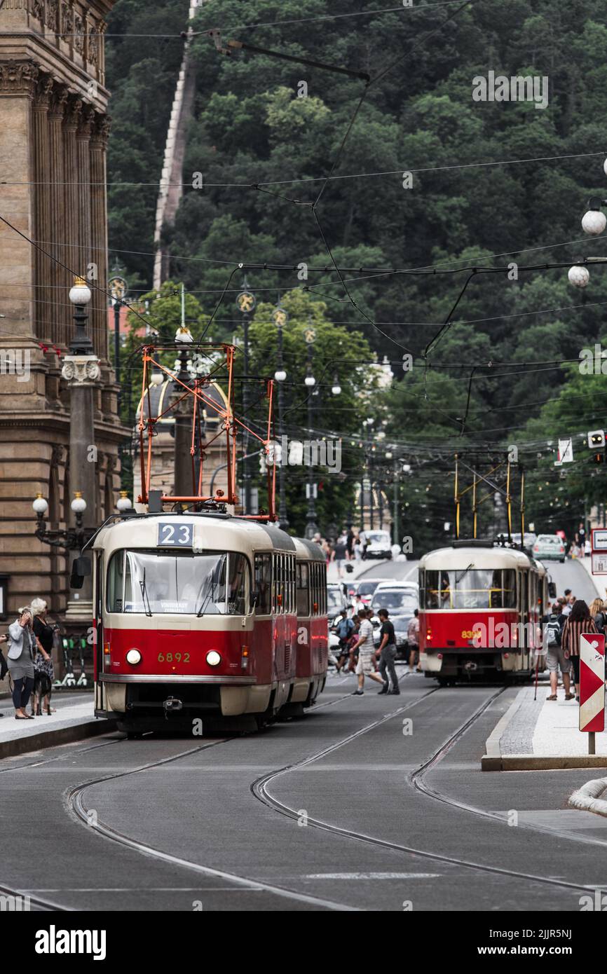 A vertical shot of two classic trams surrounded by people in Prague ...