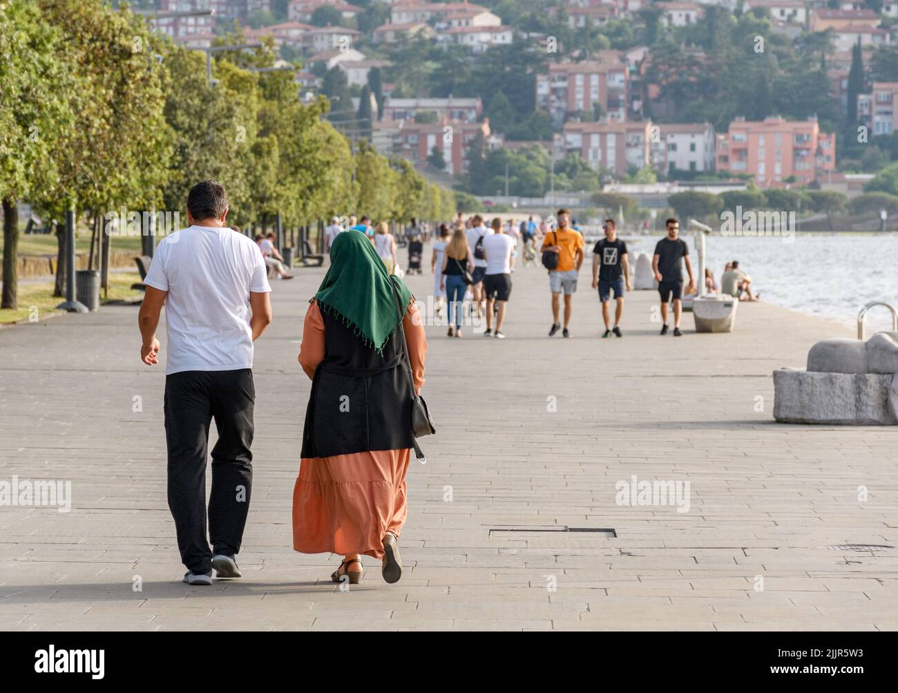 The diverse people walking on the waterfront promenade in Koper ...