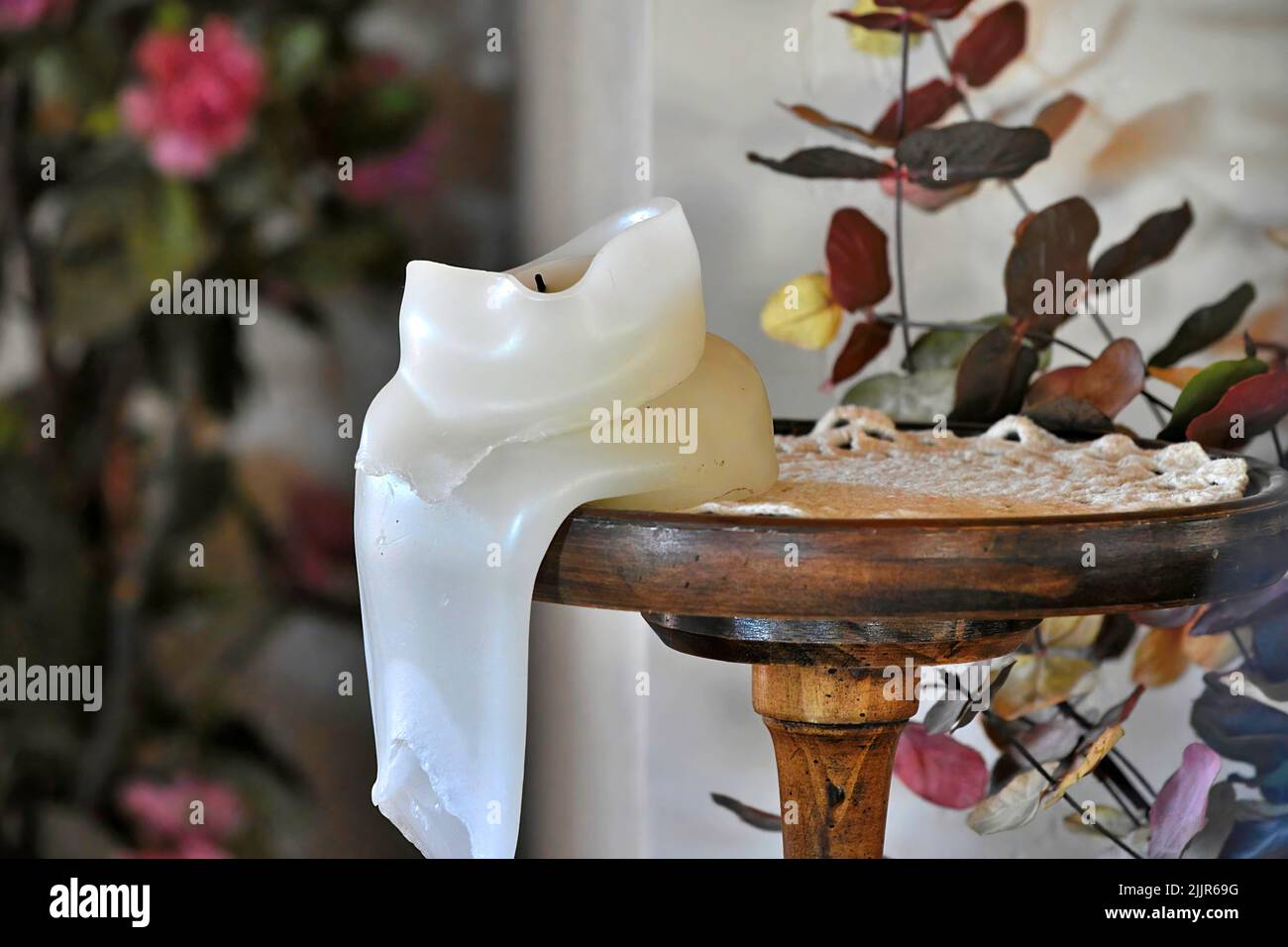 A white, pillar candle that had burned and melted down sets on the edge ...