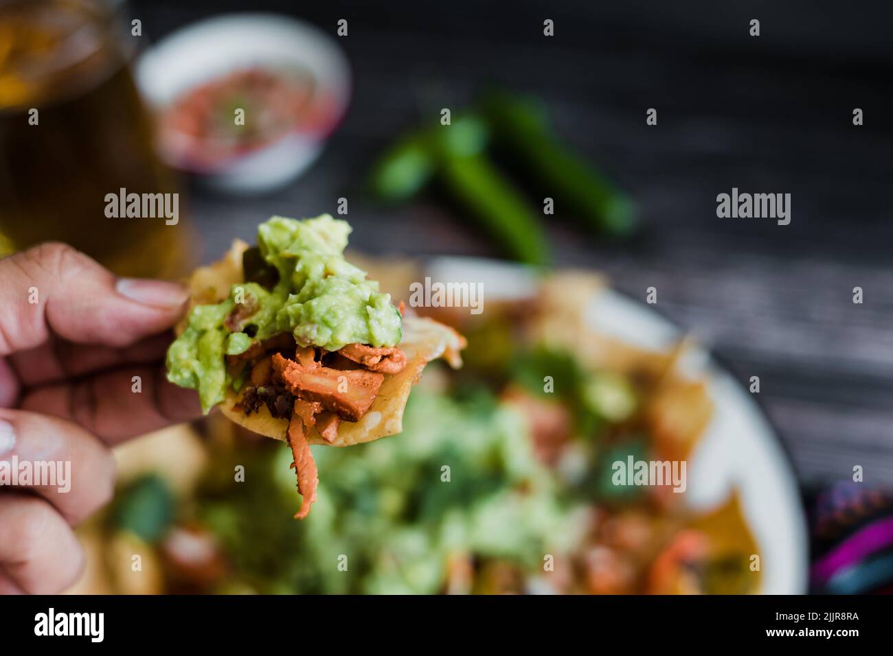 Hand holding mexican nacho chips with american cheese and avocado ...