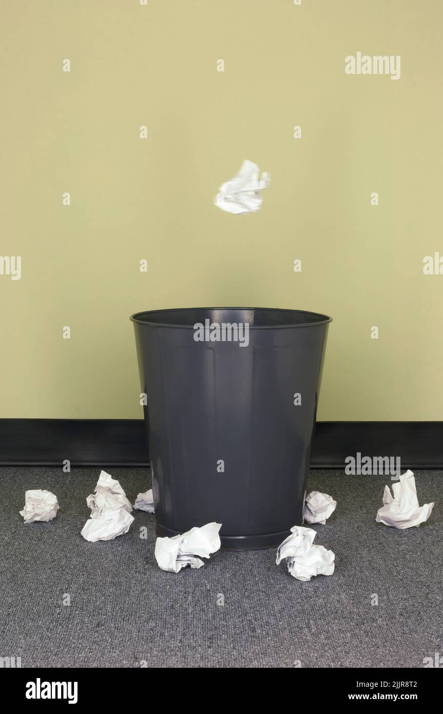 A vertical shot of paper balls dropped next to a recycling bin Stock ...