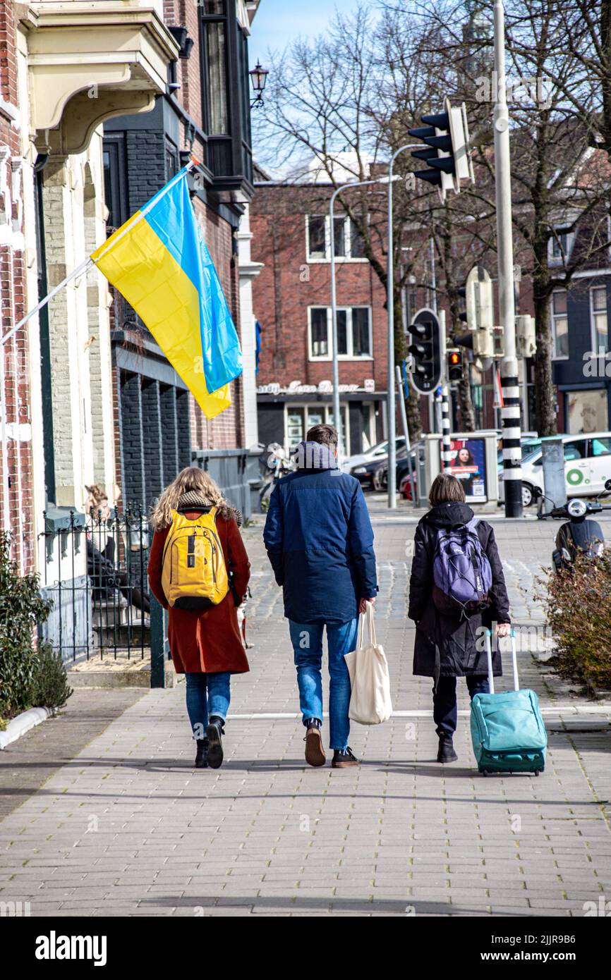 The pedestrians walk past a Ukrainian flag hanging in support of the ...