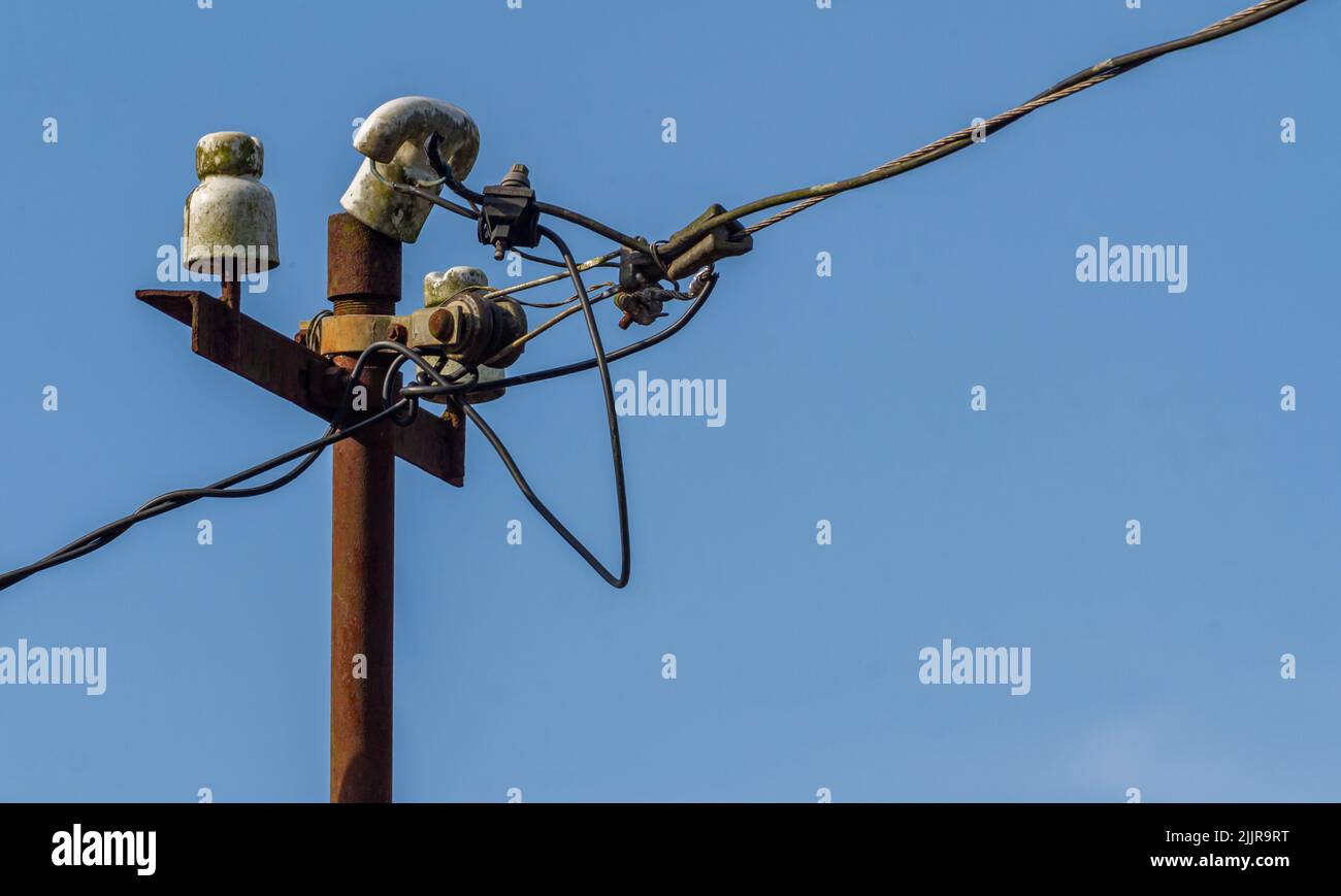 An old power pole supporting high voltage power lines, clear sky ...