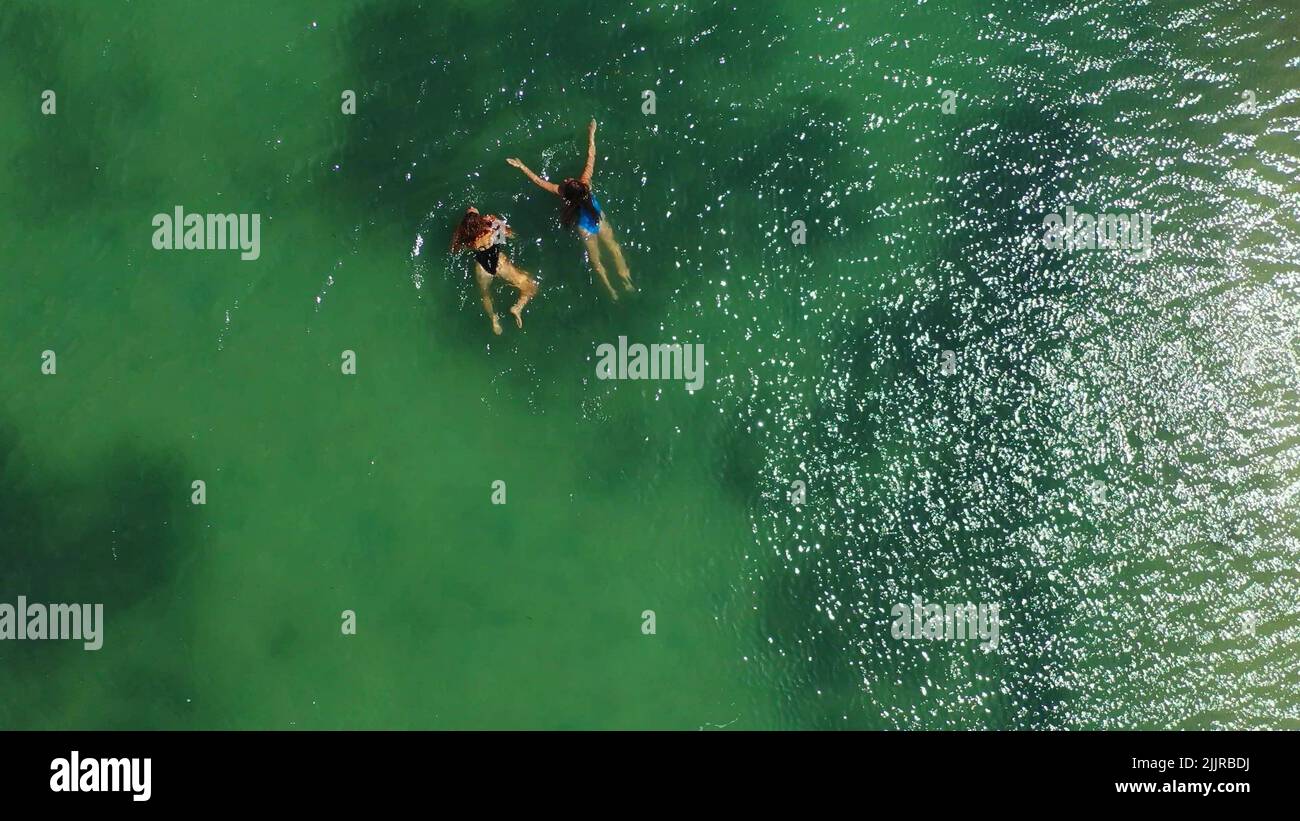 An overhead shot of two women swimming in the clear seawater in Koh ...