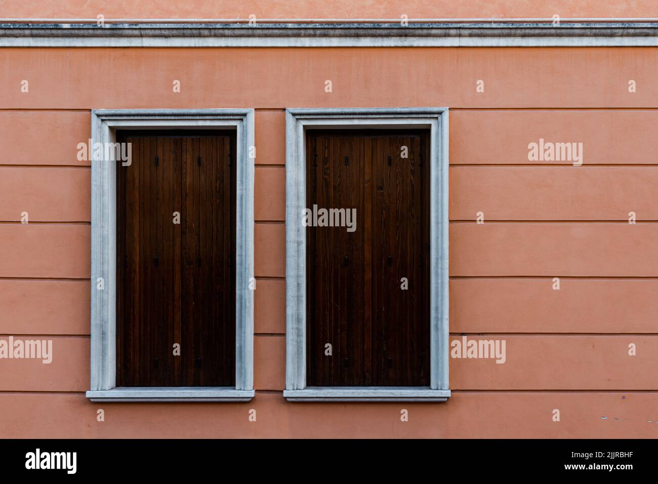 Two white windows covered with wooden boards of a pink building Stock ...