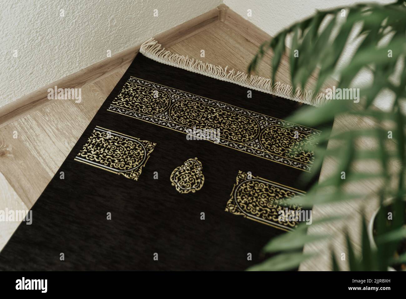A top view of a black velvet prayer mat with a Kaaba pattern in the ...