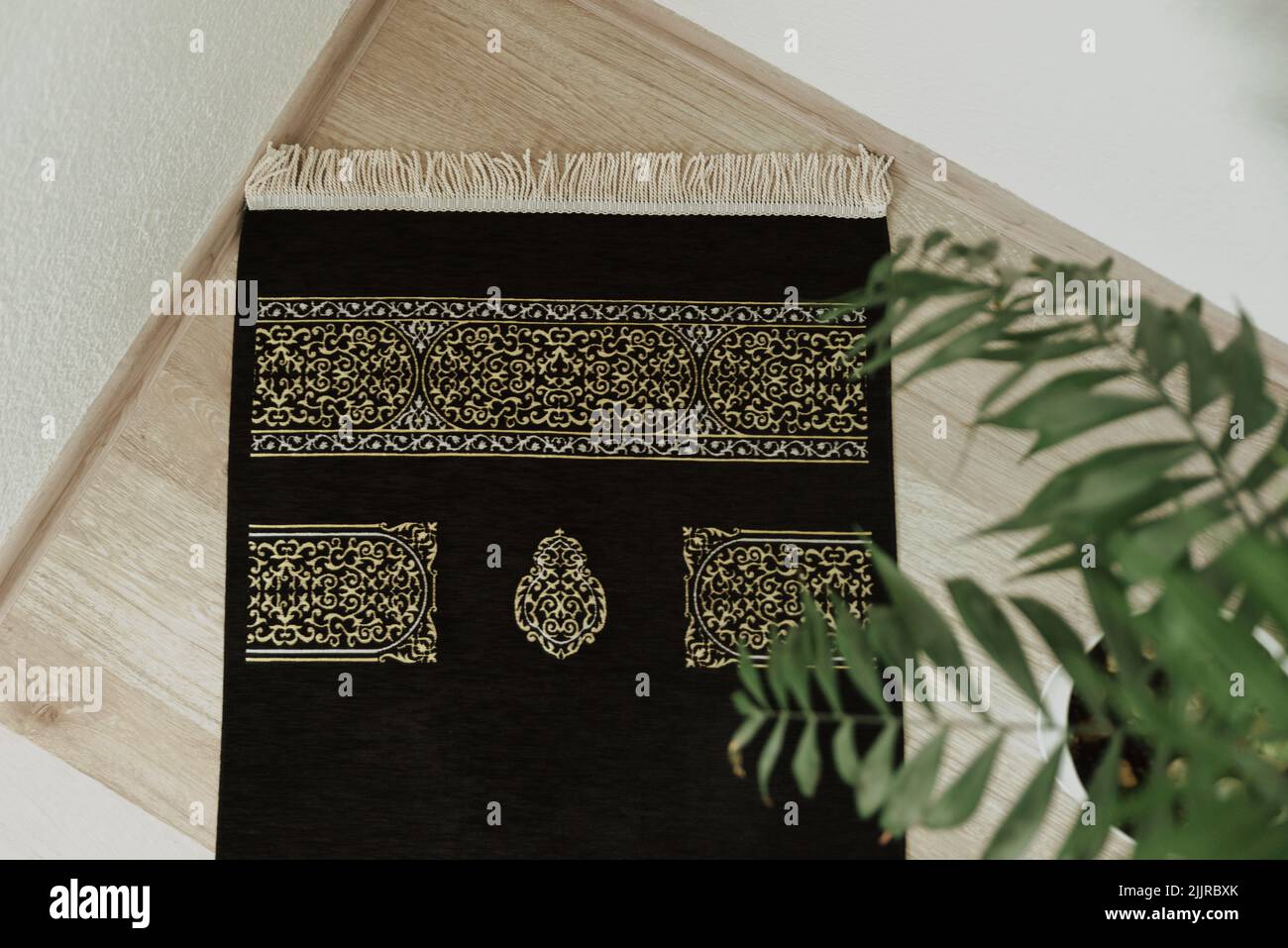 A top view of a black velvet prayer mat with a Kaaba pattern in the ...