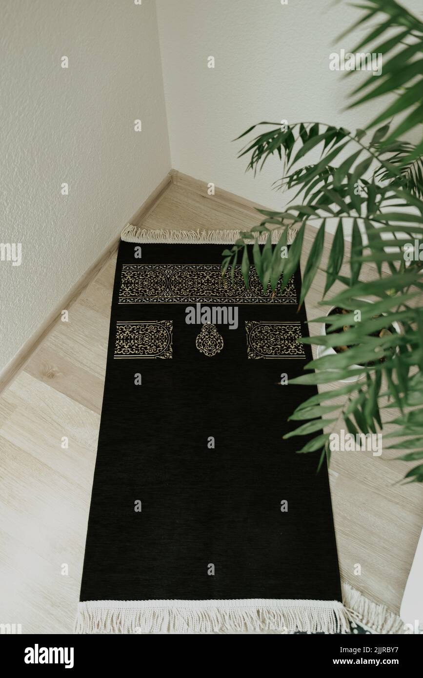 A top view of a black velvet prayer mat with a Kaaba pattern in the ...