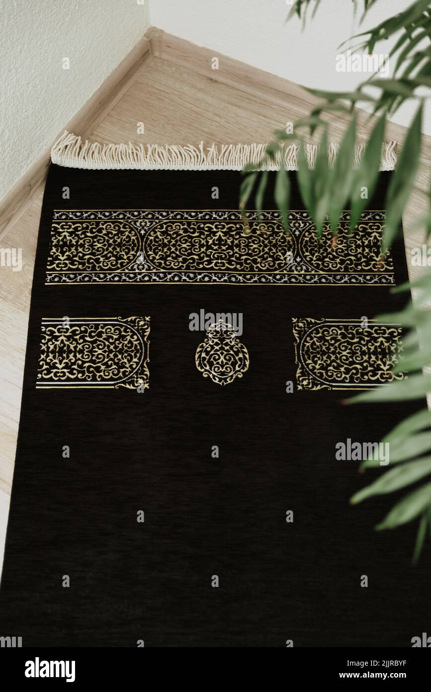 A top view of a black velvet prayer mat with a Kaaba pattern in the ...