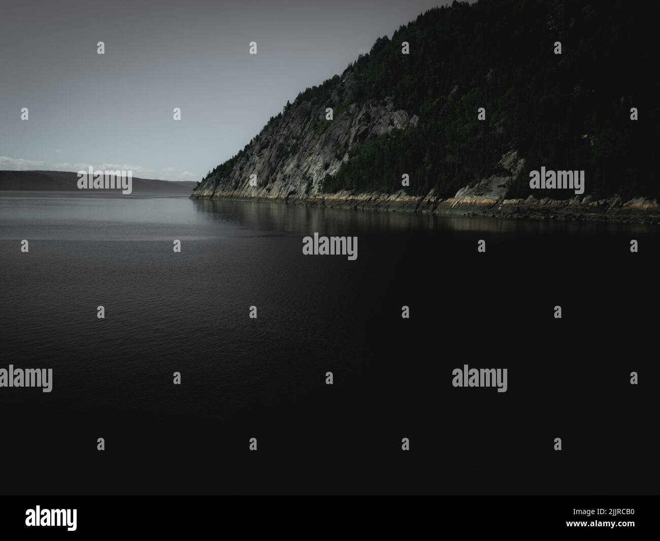 An overcast view of a beach with mountains Stock Photo - Alamy