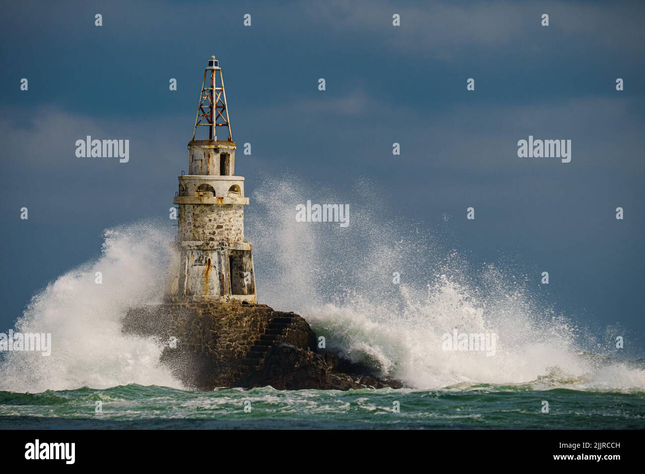 A beautiful shot of a water hitting an old lighthouse in the sea and ...