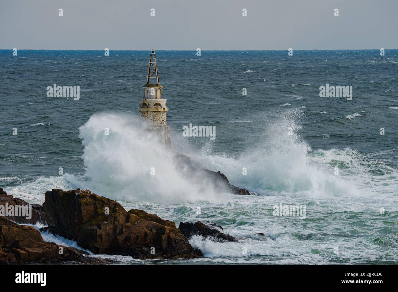 A beautiful shot of a water hitting an old lighthouse in the sea and ...