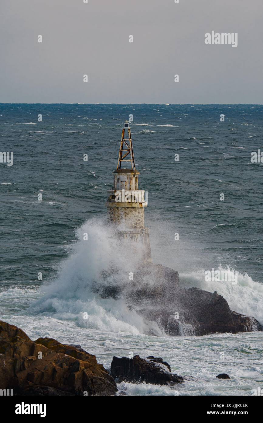 A beautiful shot of a water hitting an old lighthouse in the sea and ...
