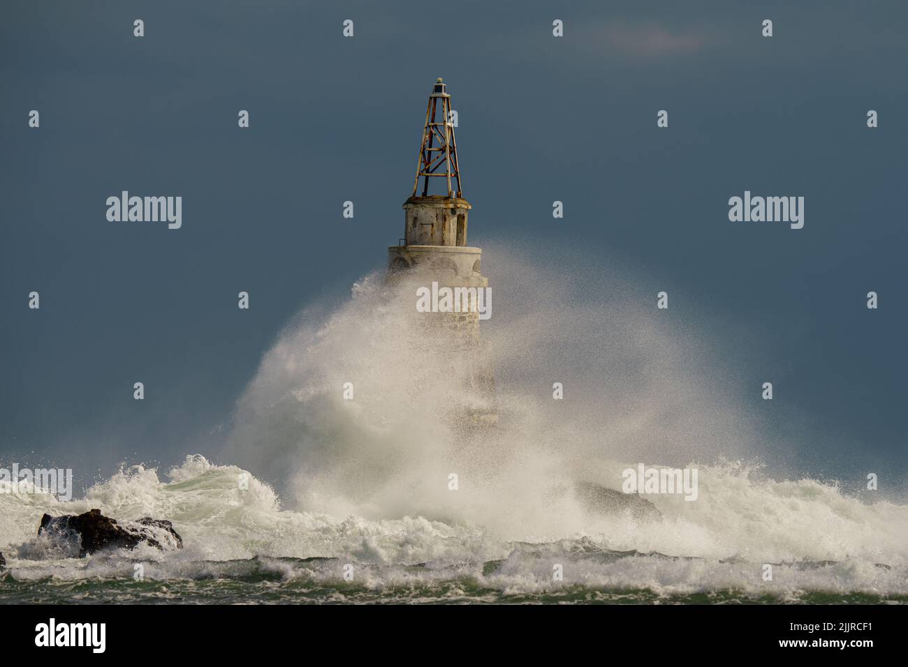 A beautiful shot of a water hitting an old lighthouse in the sea and ...